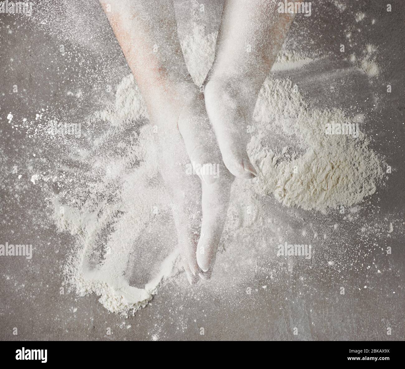 bakers hands with flour in motion on grey kitcen table background, top ...