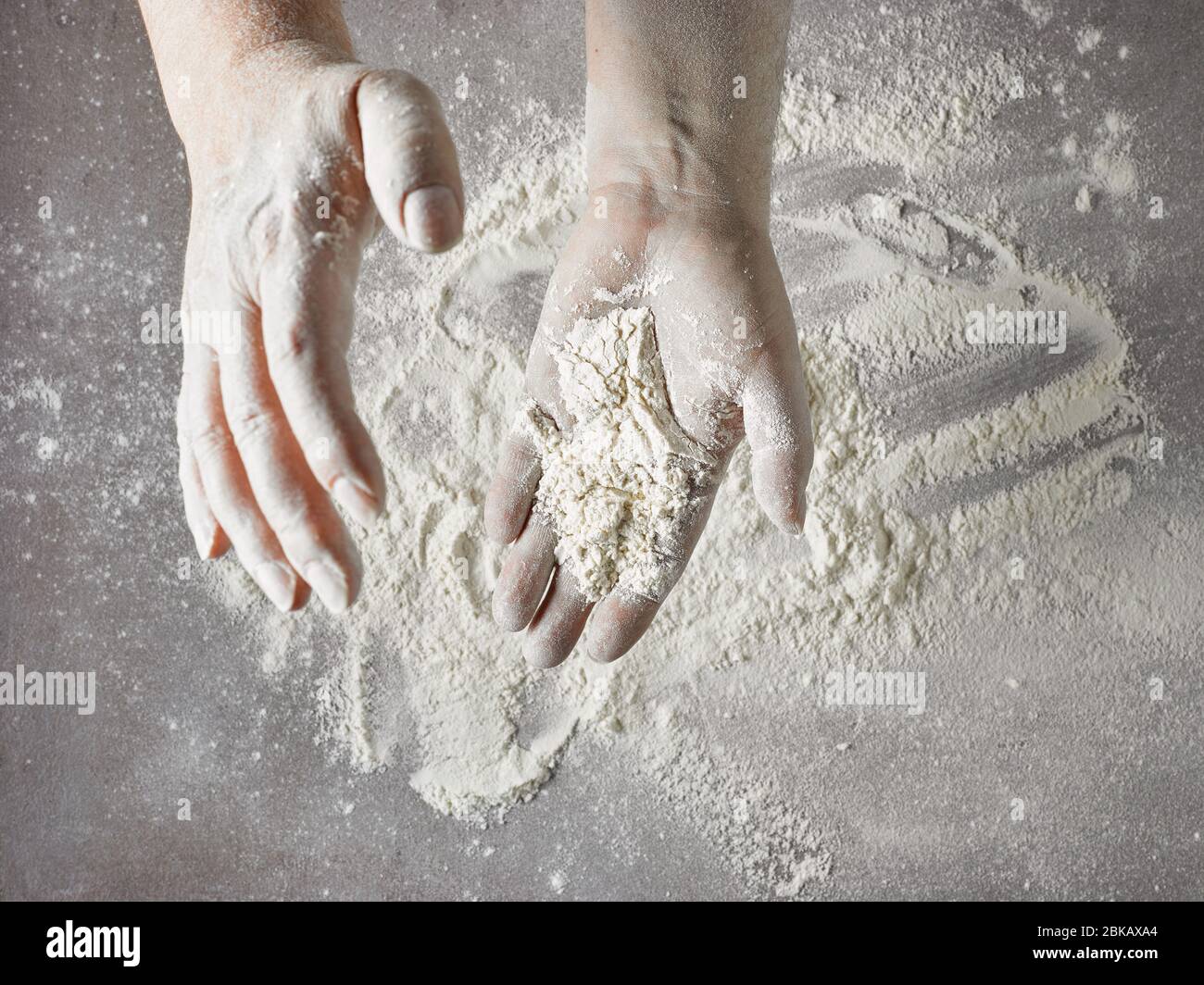 baker hands with flour in motion on grey kitcen table background, top ...