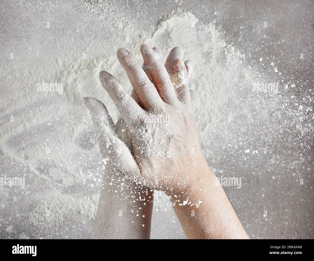baker hands with flour in motion on grey kitcen table background, top ...