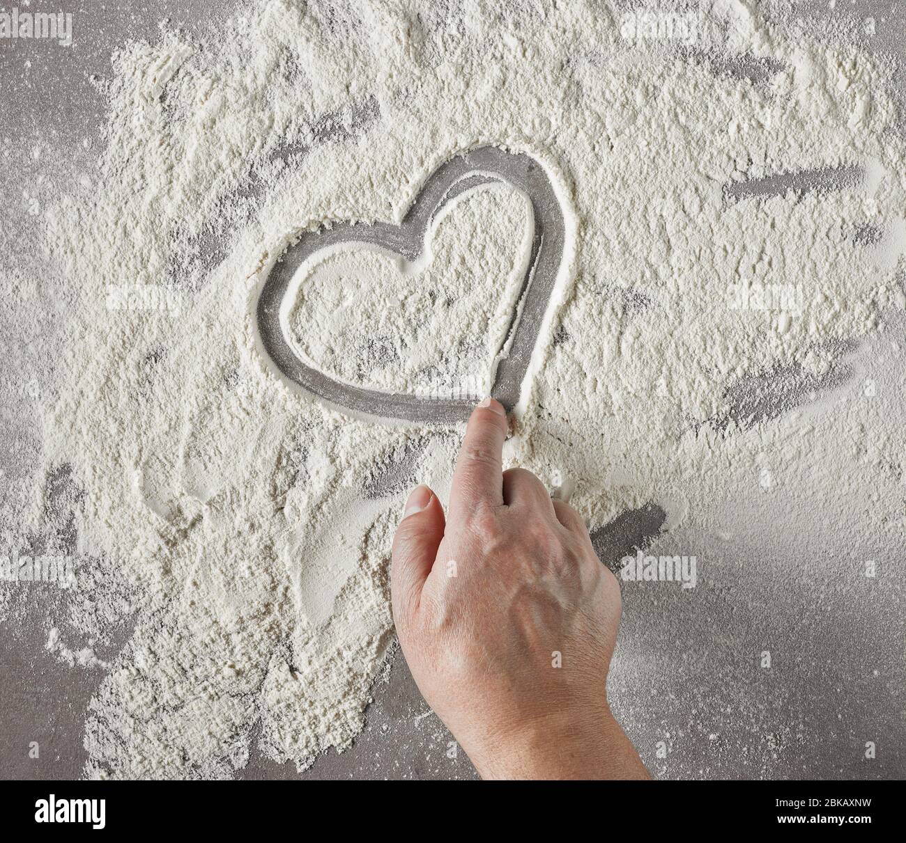 cook hand drawing heart shape in flour on grey table, top view Stock ...