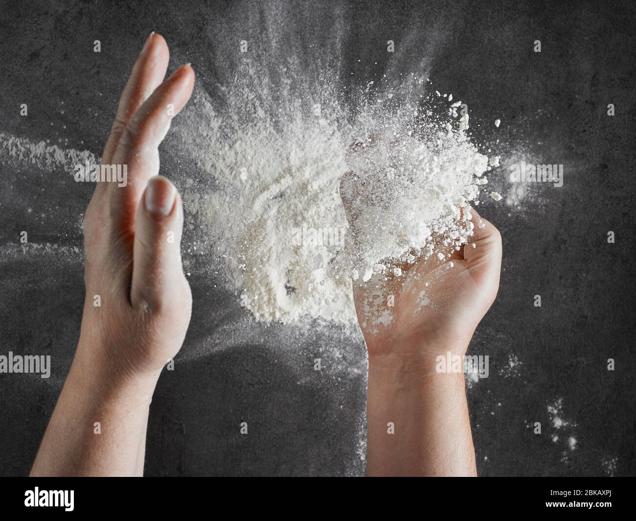 baker hands with flour in motion on grey kitcen table background, top ...