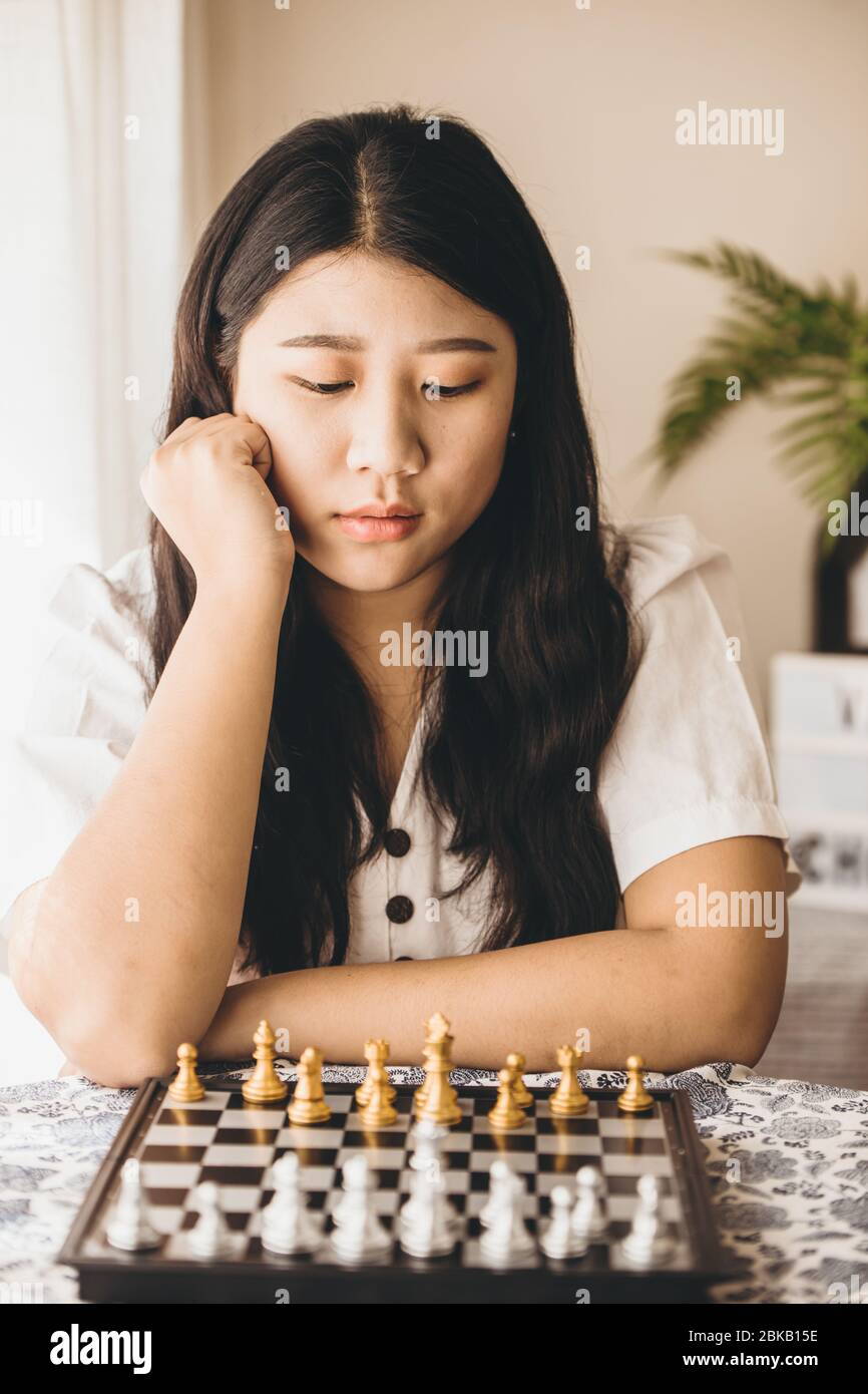 Smart girl teen thinking while playing Chess boardgame at home for ...