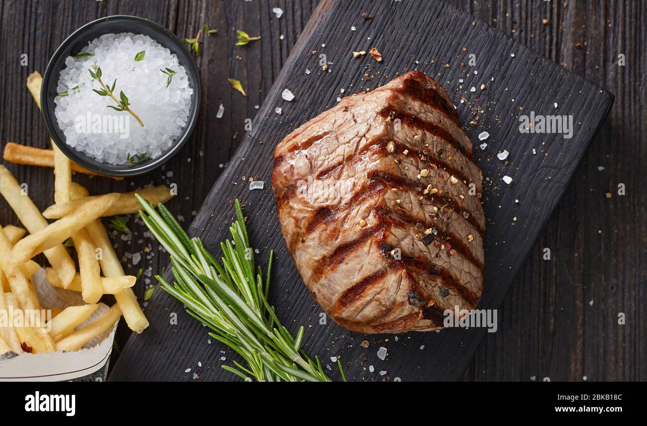 grilled beef steak on dark wood table, top view Stock Photo - Alamy