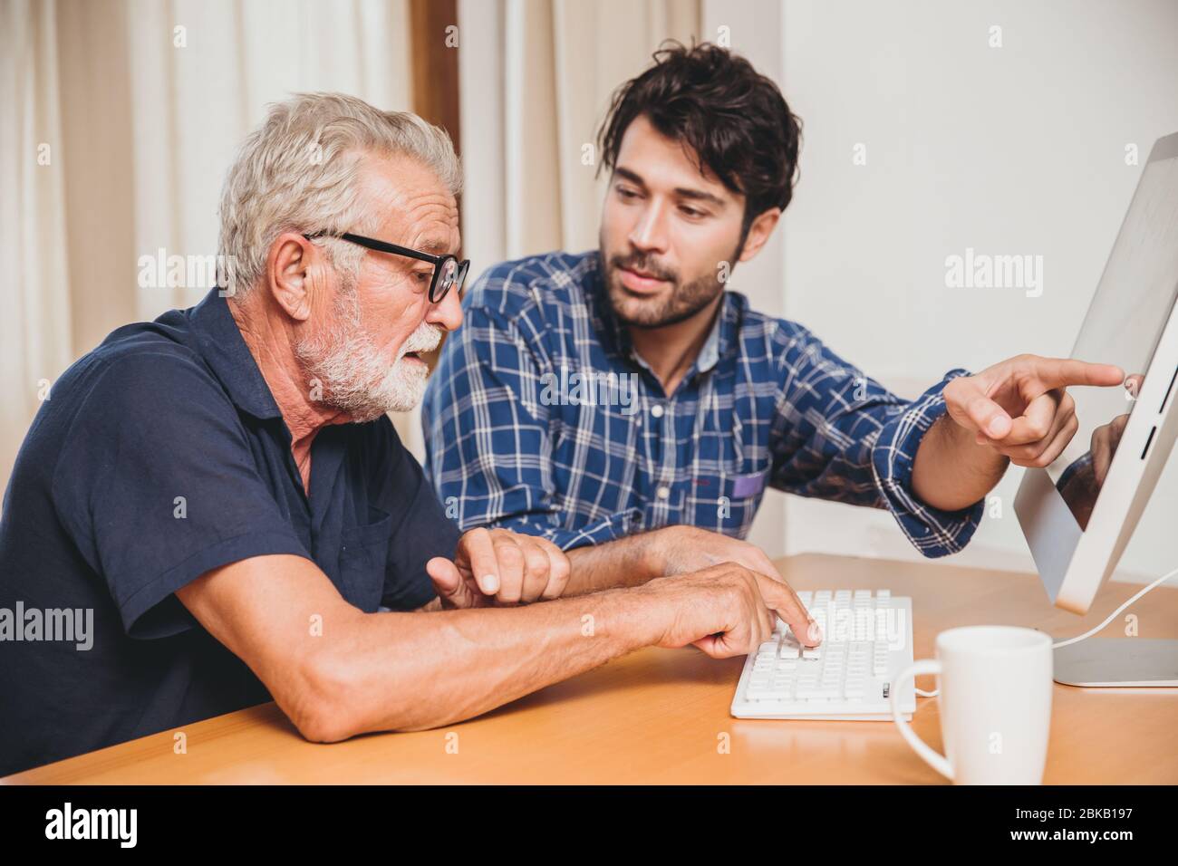 young man or son teaching his grandfather elderly dad learning to using ...