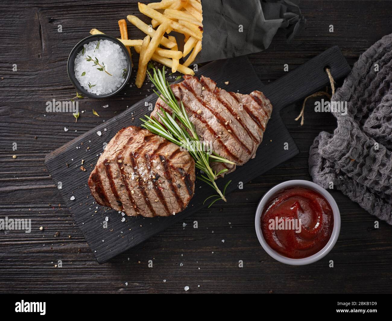 grilled beef steaks on dark wood table, top view Stock Photo - Alamy