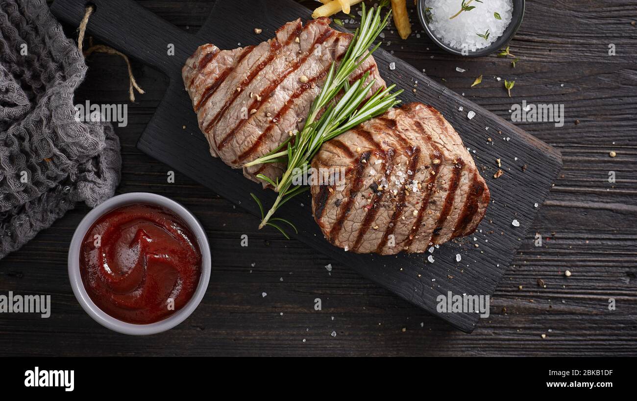 grilled beef steaks on dark wood table, top view Stock Photo - Alamy
