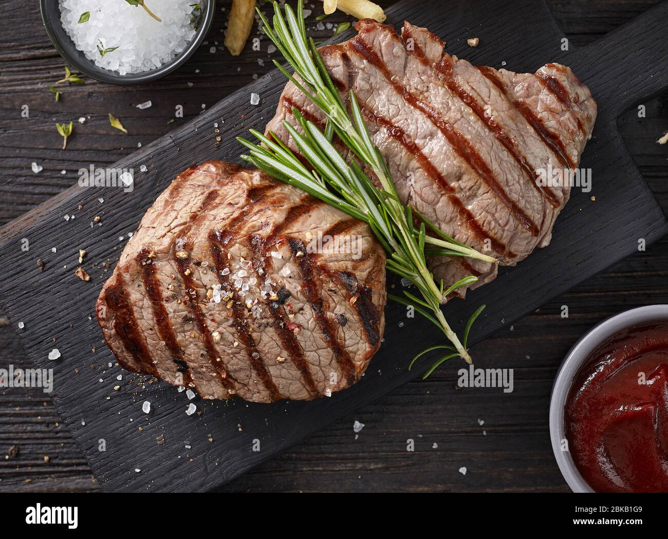 grilled beef steaks on dark wood table, top view Stock Photo - Alamy