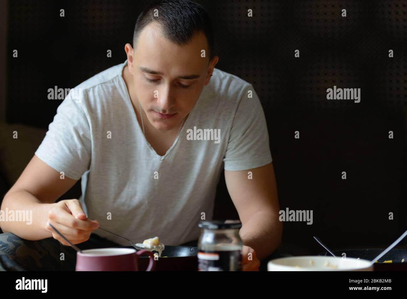 Portrait of handsome man eating in the living room Stock Photo - Alamy