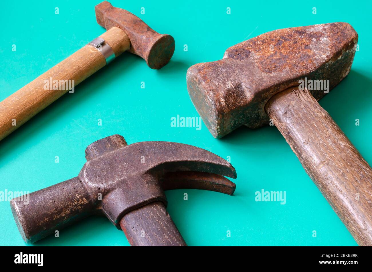 Vintage hammers on a turquoise background. Three old rusty hammers on a ...