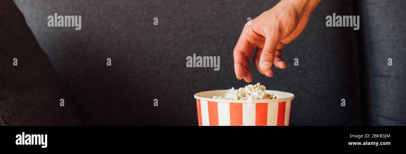 panoramic crop of man reaching popcorn in bucket Stock Photo - Alamy