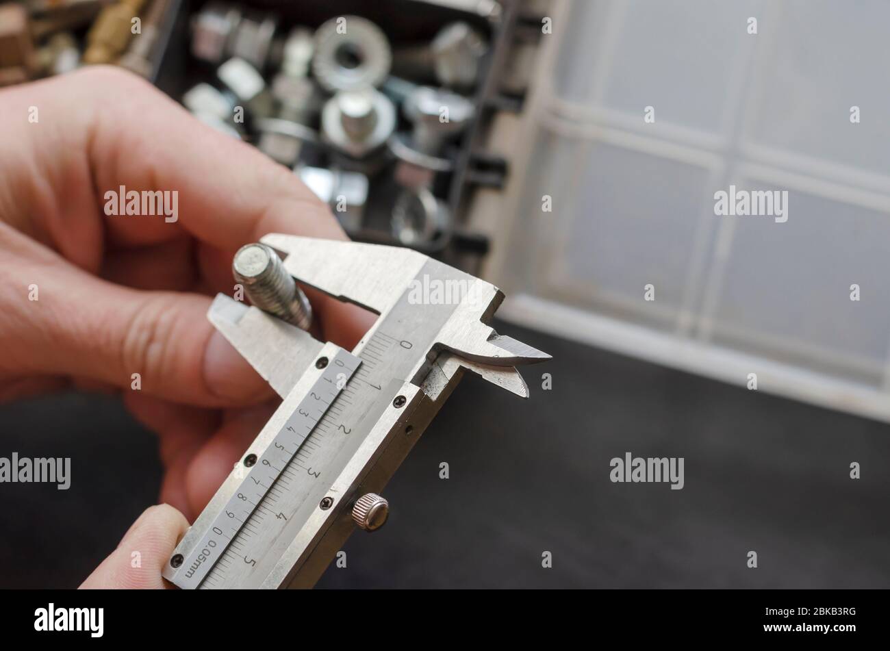 A male hand with a caliper measures the diameter of a bolt. Choosing ...