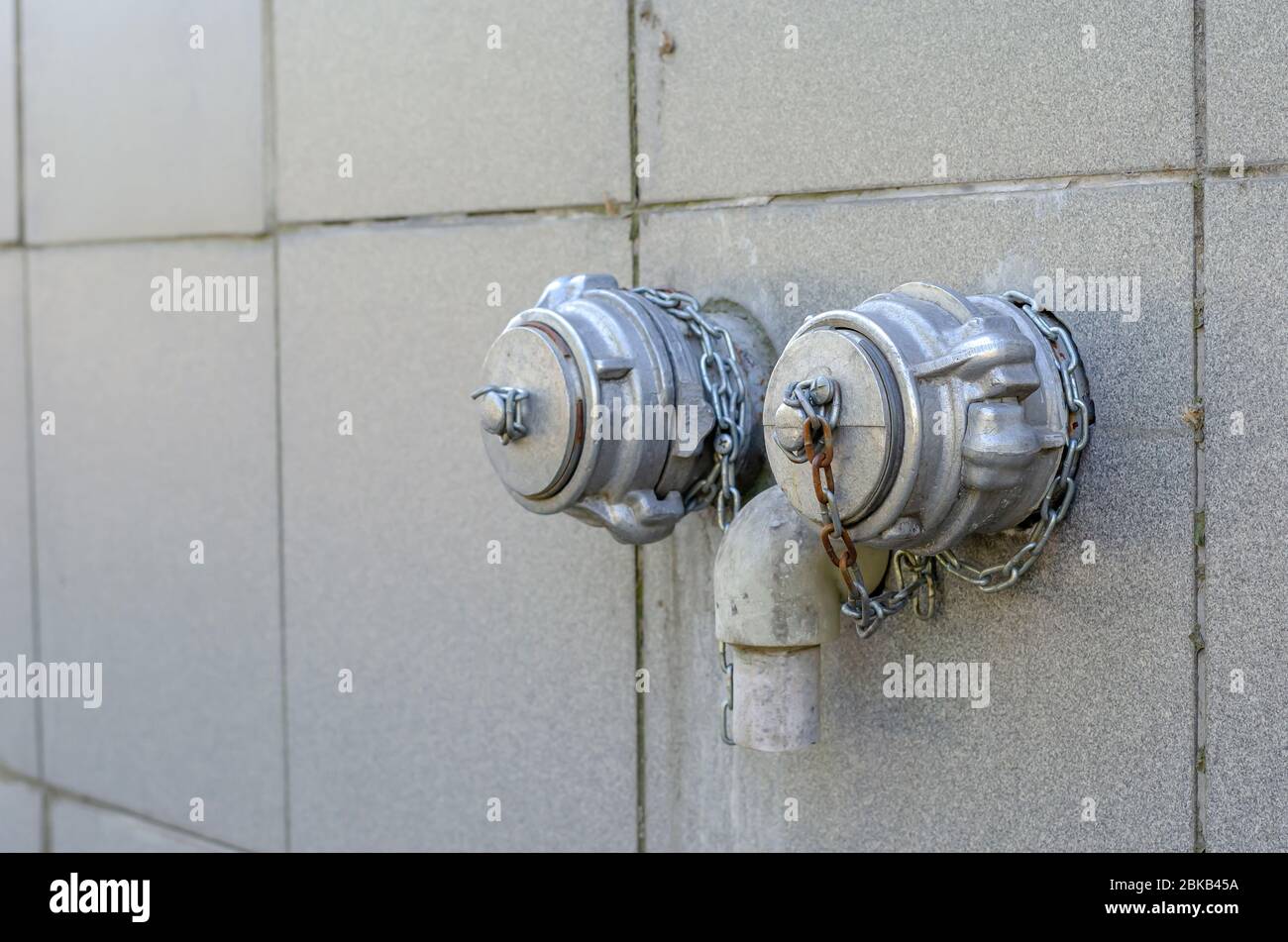 Aluminum fire hydrants in the wall with covers on chains. Two fire ...