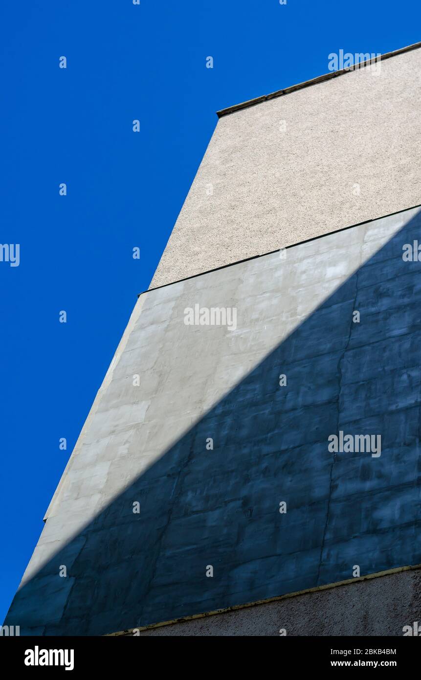 Concrete wall against the blue sky. The play of light and shadow on the ...