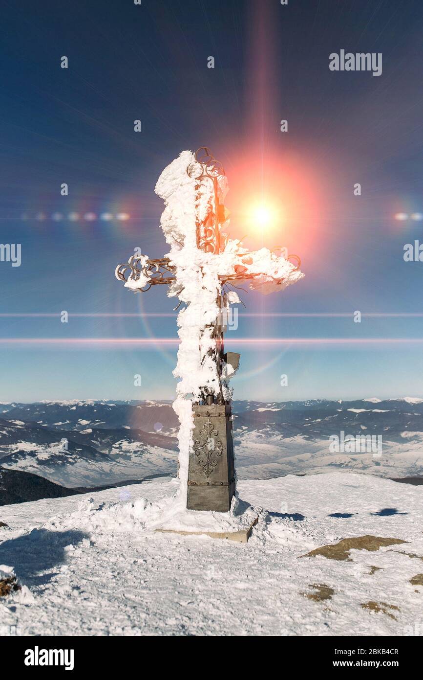snow-covered cross in the mountains with the sun Stock Photo - Alamy