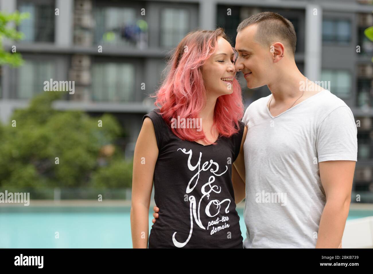 Portrait of happy couple nose to nose together in the swimming pool ...