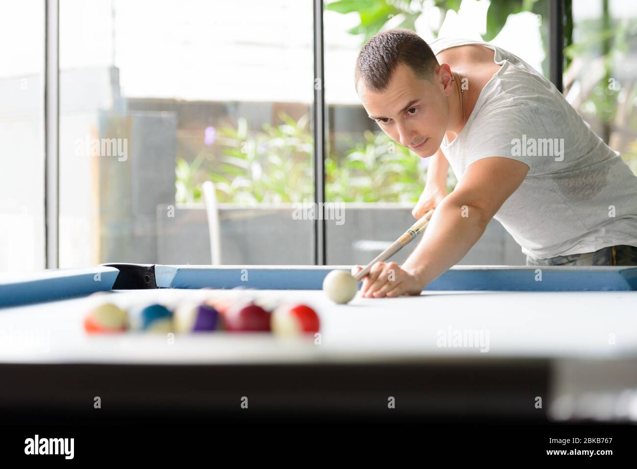 Handsome man leaning on pool table while playing billiard Stock Photo ...