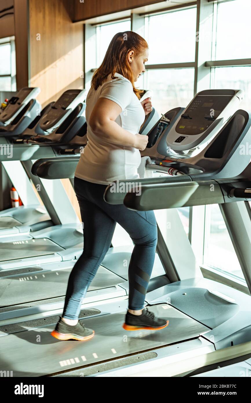 overweight girl working out on treadmill in gym near window Stock Photo ...