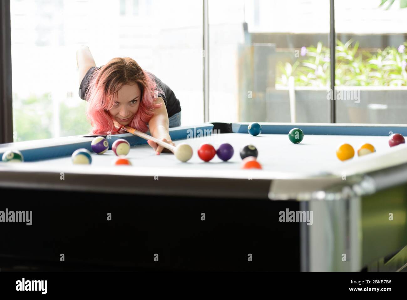 Beautiful woman with pink hair playing billiard Stock Photo - Alamy