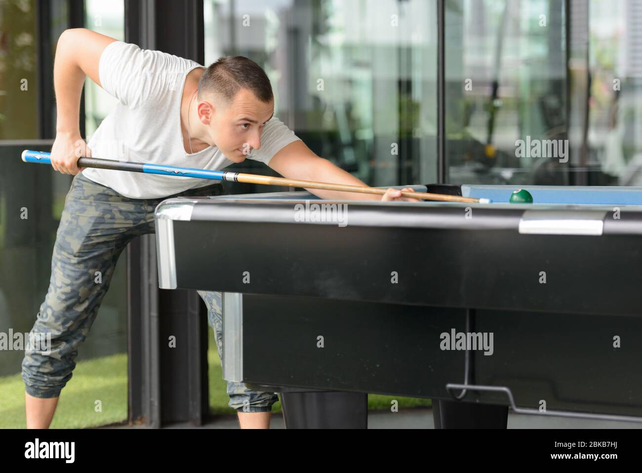 Handsome man leaning on pool table while playing billiard Stock Photo ...