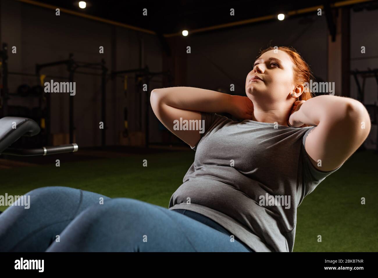 pretty, overweight girl doing abs with hands behind head in gym Stock ...