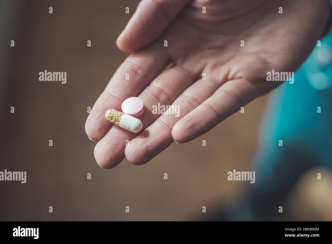 Male hand holding drug or vitamin pill in Stock Photo - Alamy