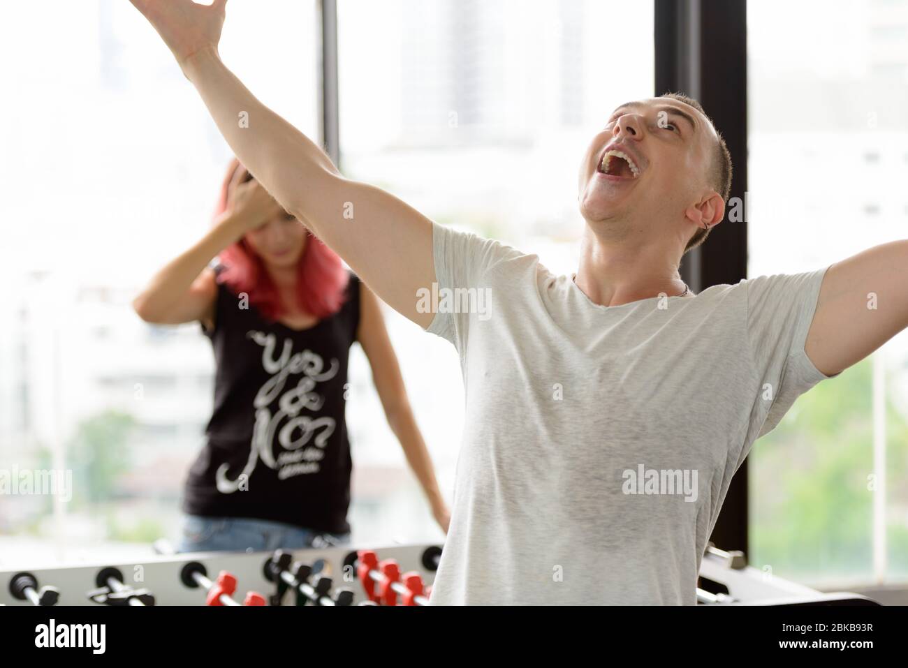 Portrait of couple playing Foosball together with man as winner Stock ...