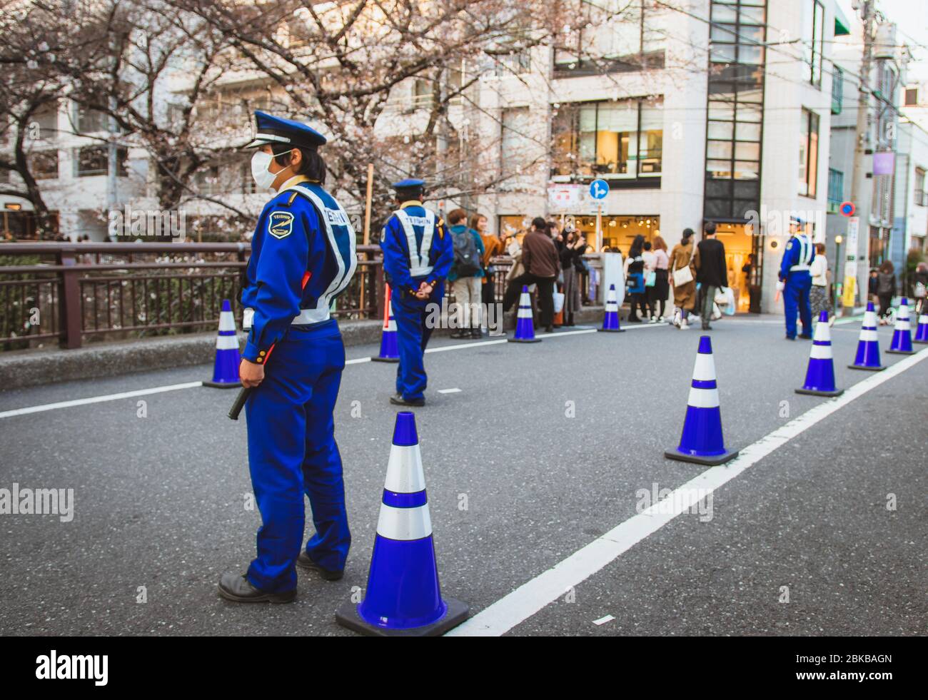 Security guards direct and maintain traffic on a bridge at Meguro River ...