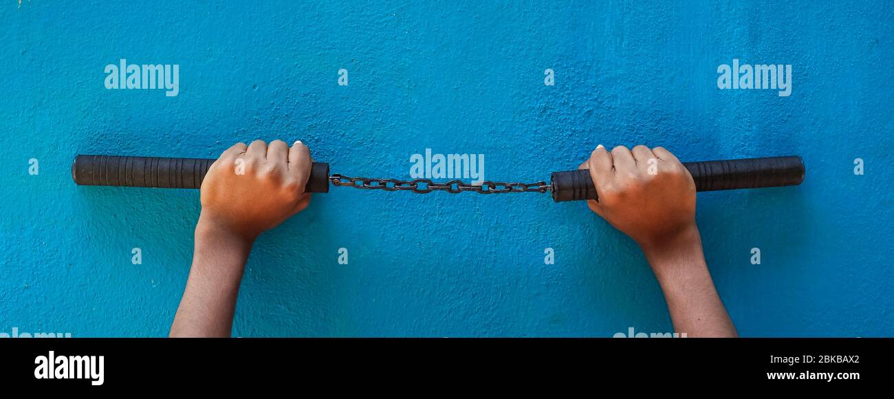 Nunchaku holding on hand isolated on Blue background. Black nunchaku ...