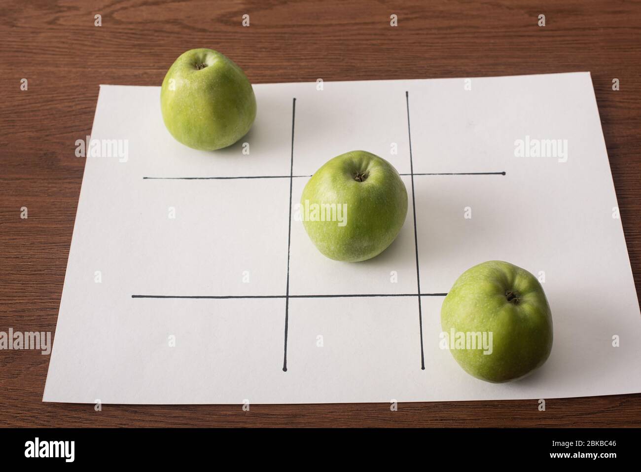 tic tac toe game on white paper with row of three green apples on ...