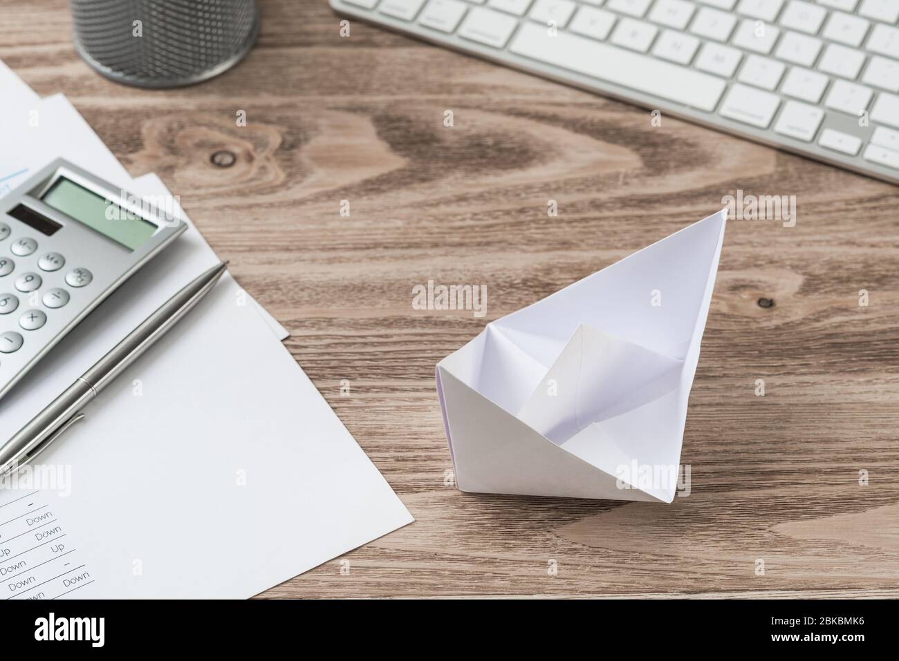 Wooden office desk with white origami boat Stock Photo - Alamy
