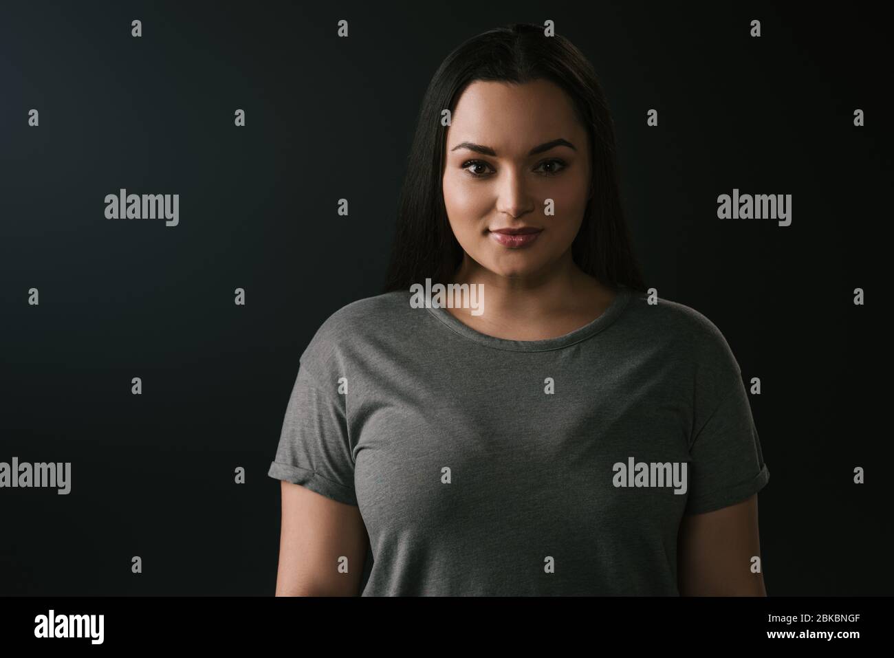 Front view of attractive smiling plus size girl on black background ...