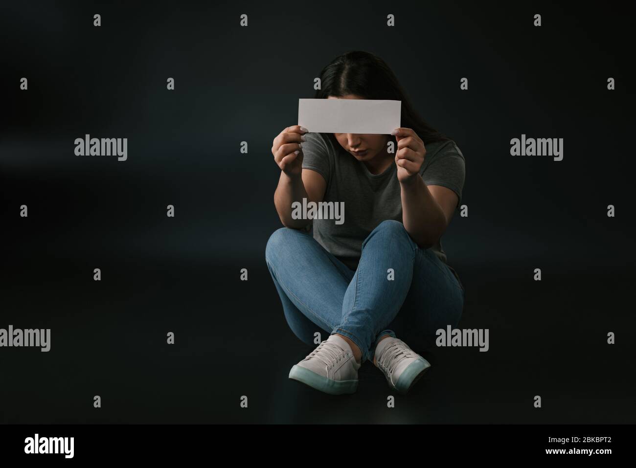 Front view of plus size sitting in crossed legs pose and covering face ...