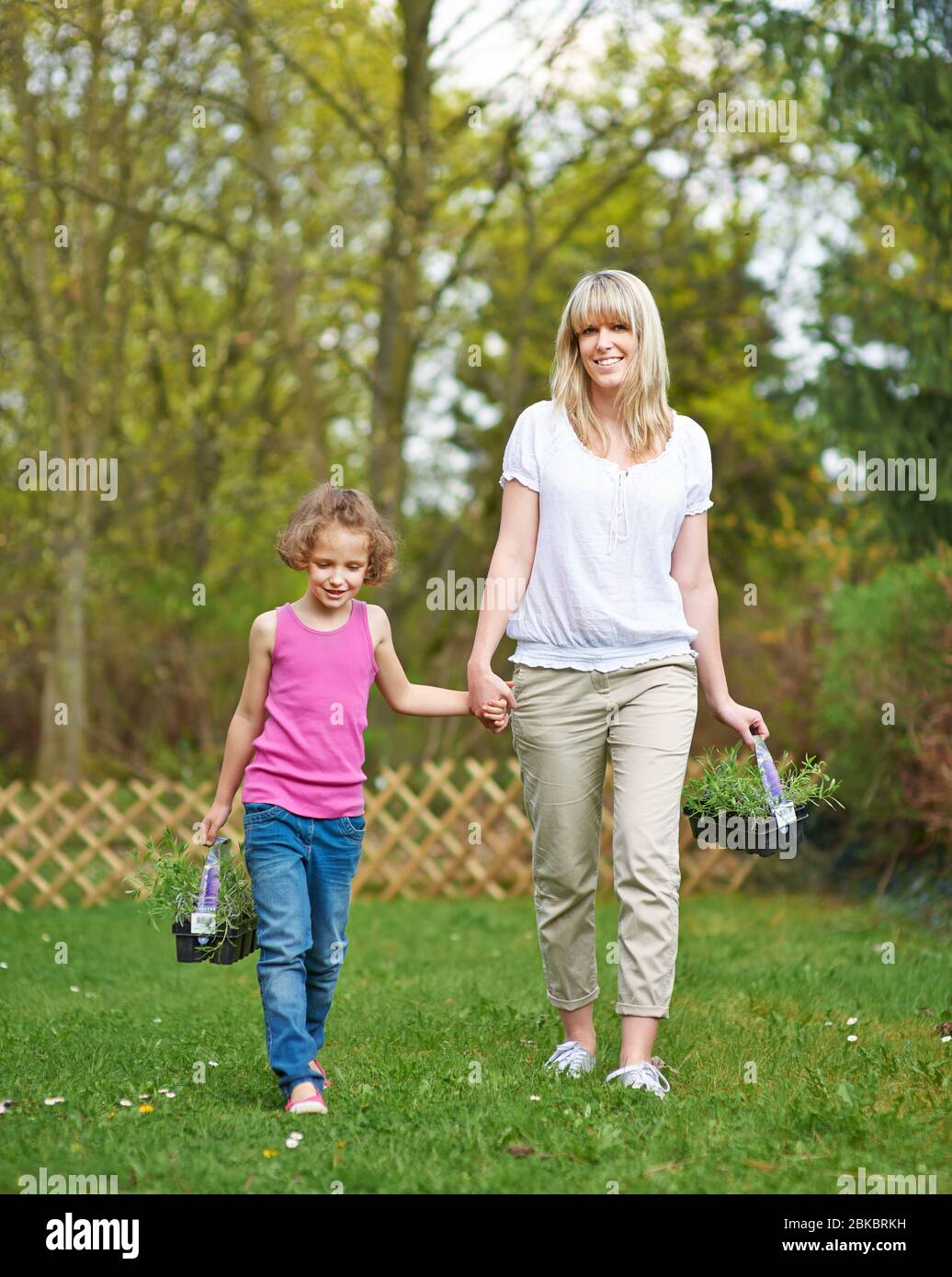 Woman and child go gardening with plants in the garden in summer Stock ...
