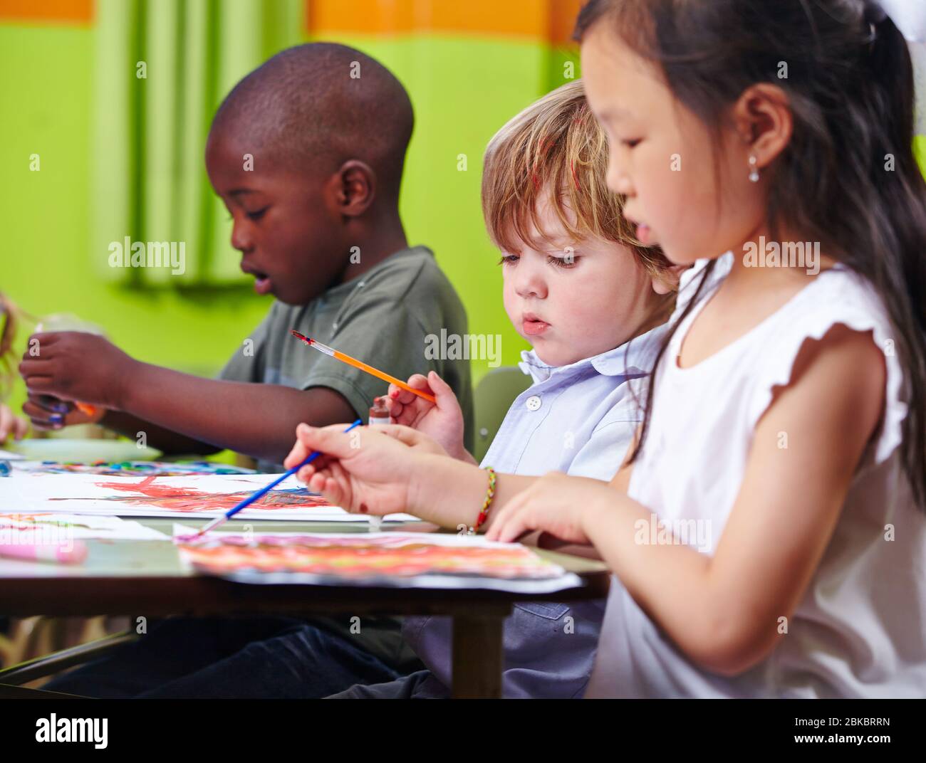 Different children concentrate together painting pictures in ...