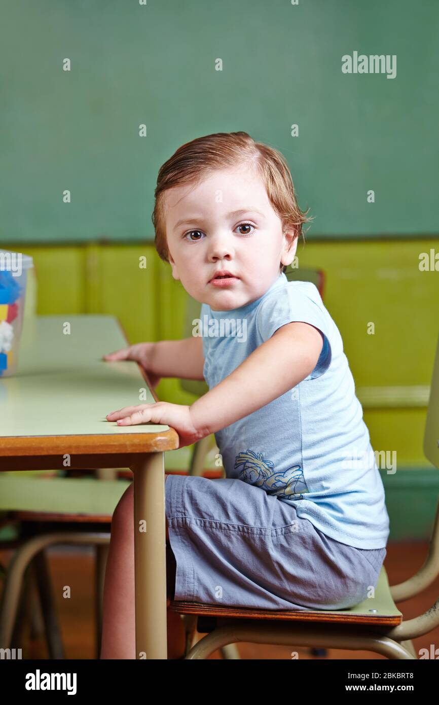 Little cute boy sits at the table in kindergarten Stock Photo - Alamy