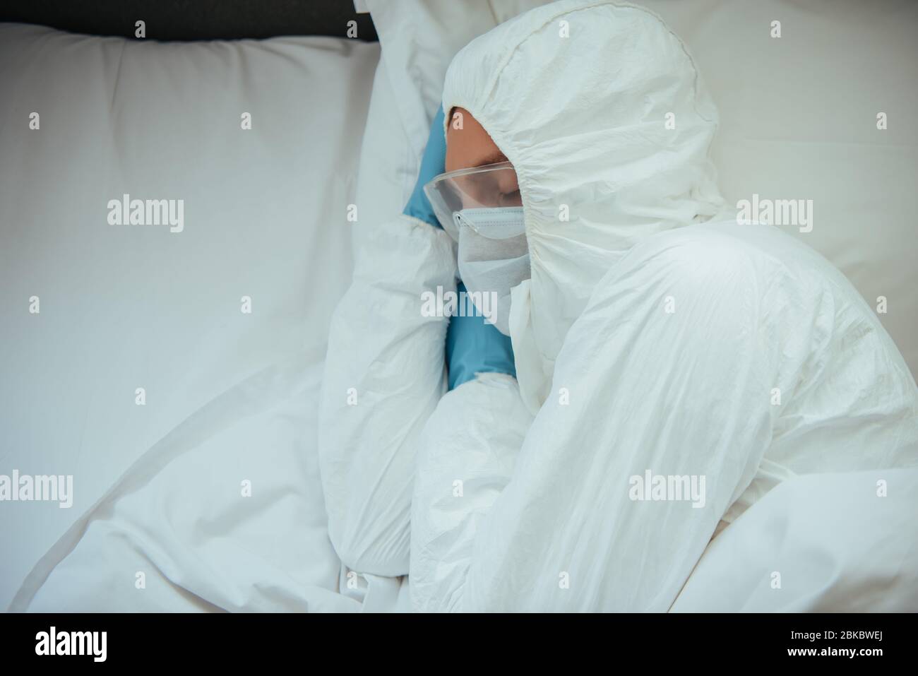 top view of man in hazmat suit, medical mask and goggles sleeping on ...