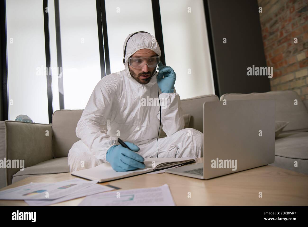 bearded operator in personal protective equipment touching headset and ...
