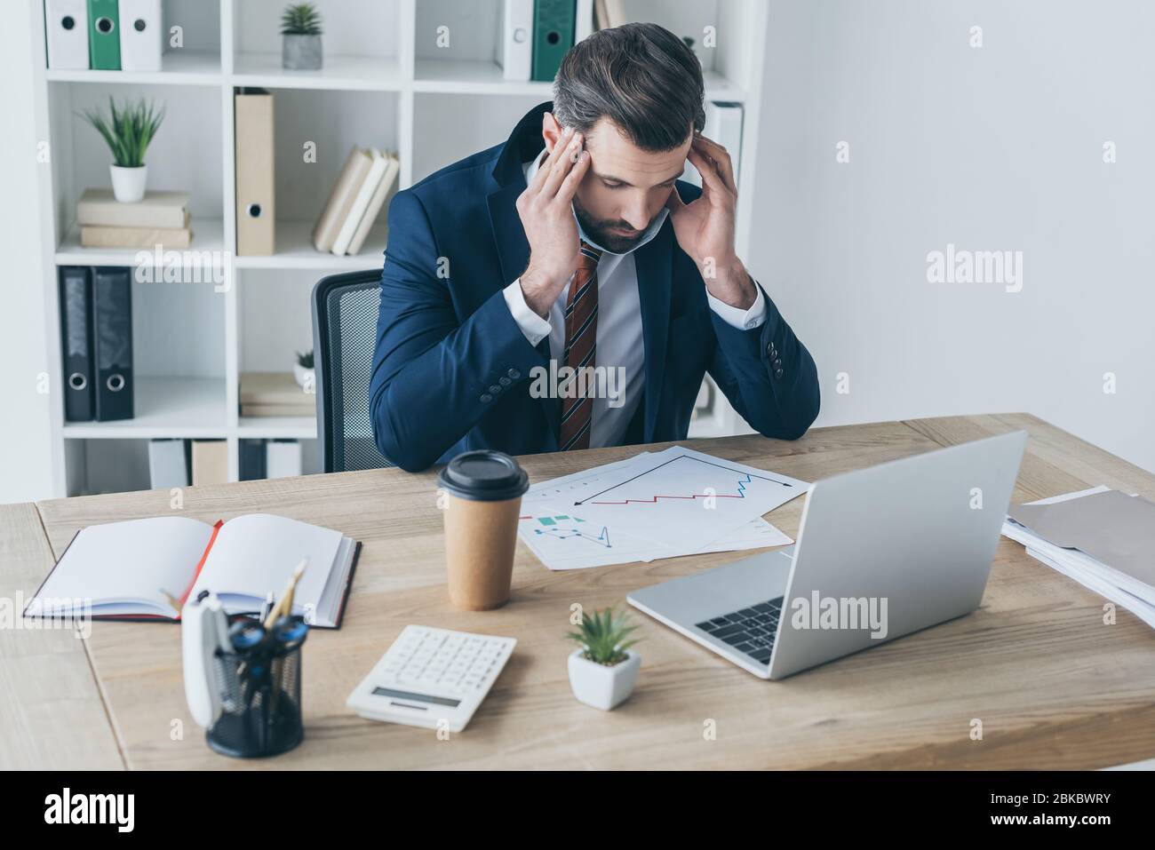 stressed, exhausted businessman touching head while sitting with closed ...
