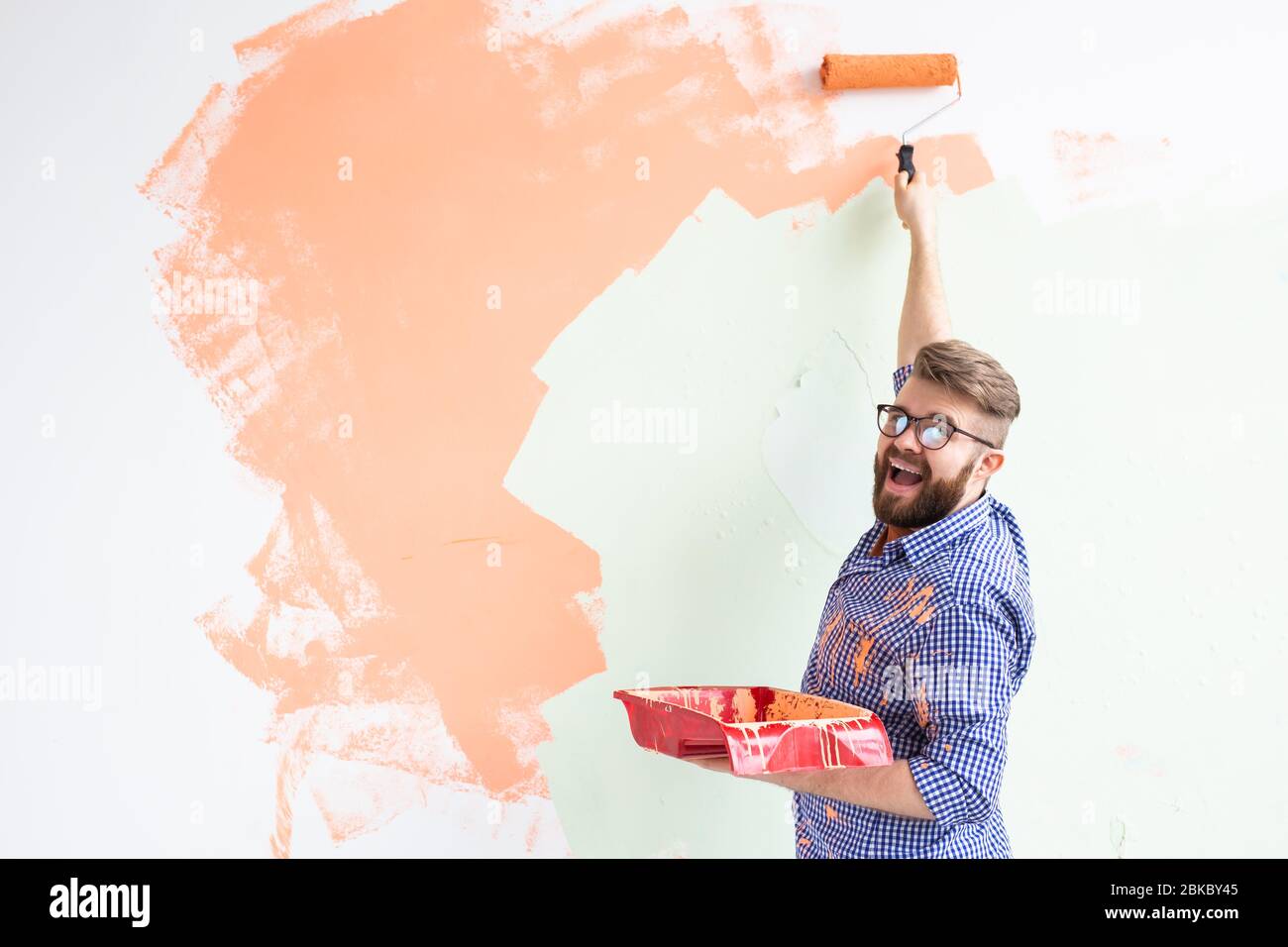 Male painting the wall with paint roller. Portrait of a funny guy ...