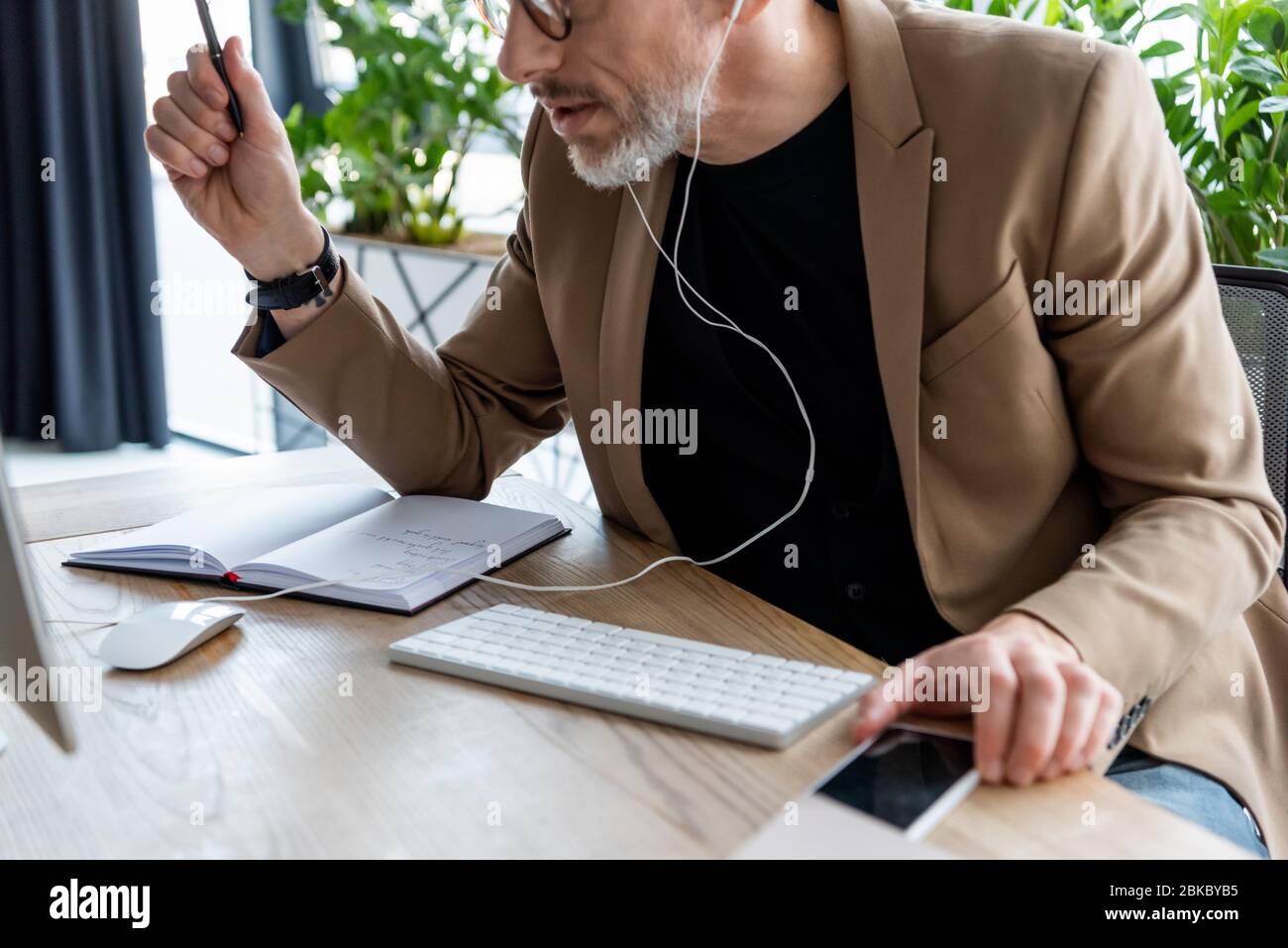 cropped view of businessman in earphones near computer monitor touching ...