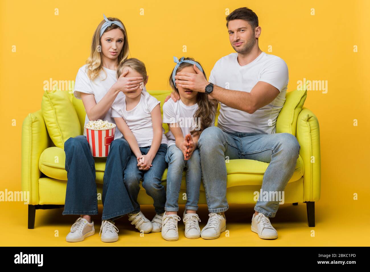 skeptical parents closing eyes to kids while watching movie on sofa ...
