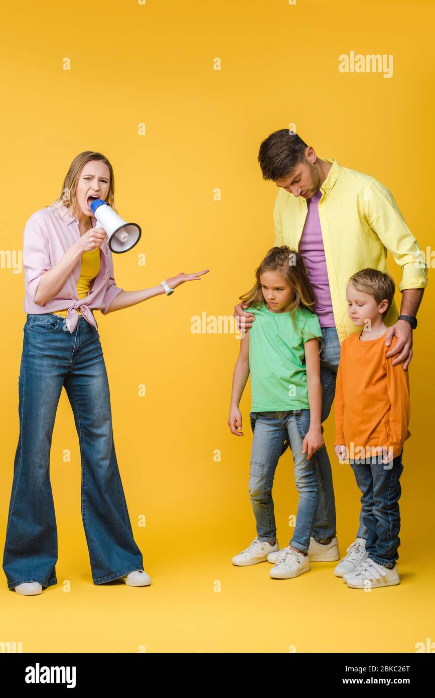 angry mother yelling into megaphone on husband and sad children on ...