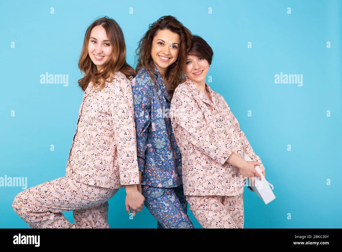 Portrait of three beautiful young girls wearing colorful pyjamas having ...