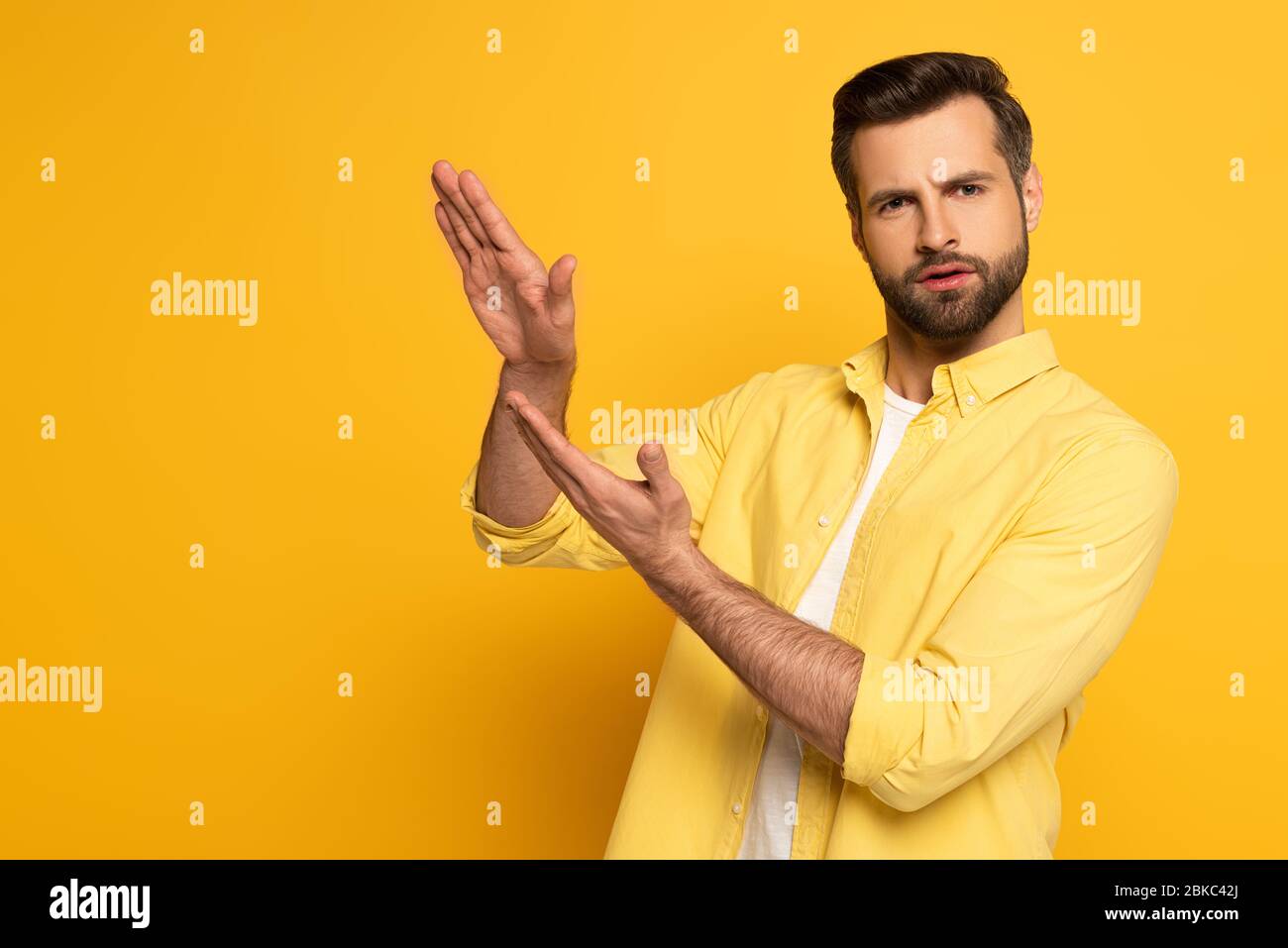 Pensive man showing gesture in sign language on yellow background Stock ...