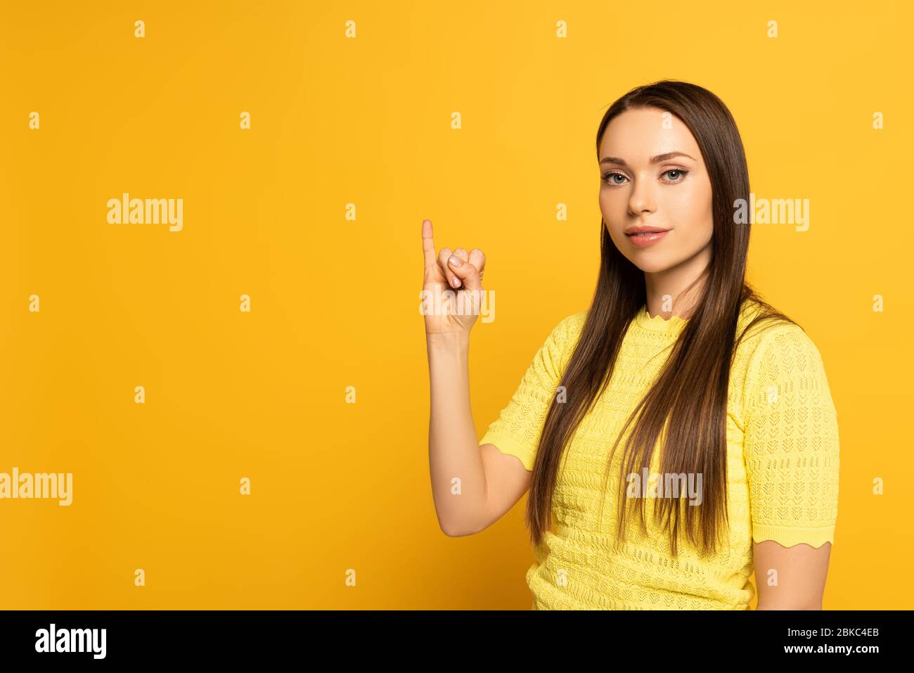 Beautiful woman showing letter from sign language on yellow background ...