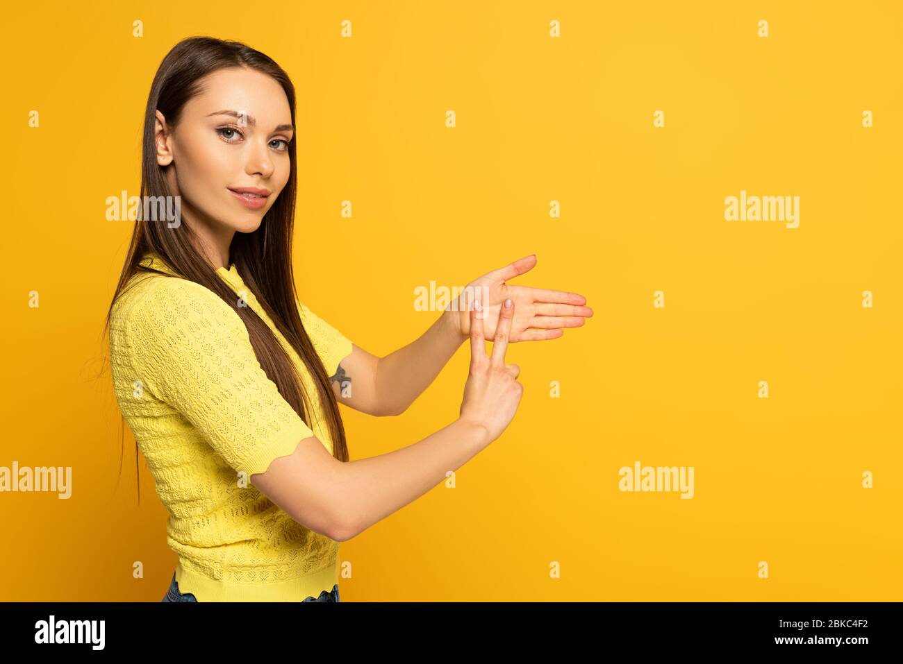 Side view of woman showing gesture in deaf and dumb language on yellow ...