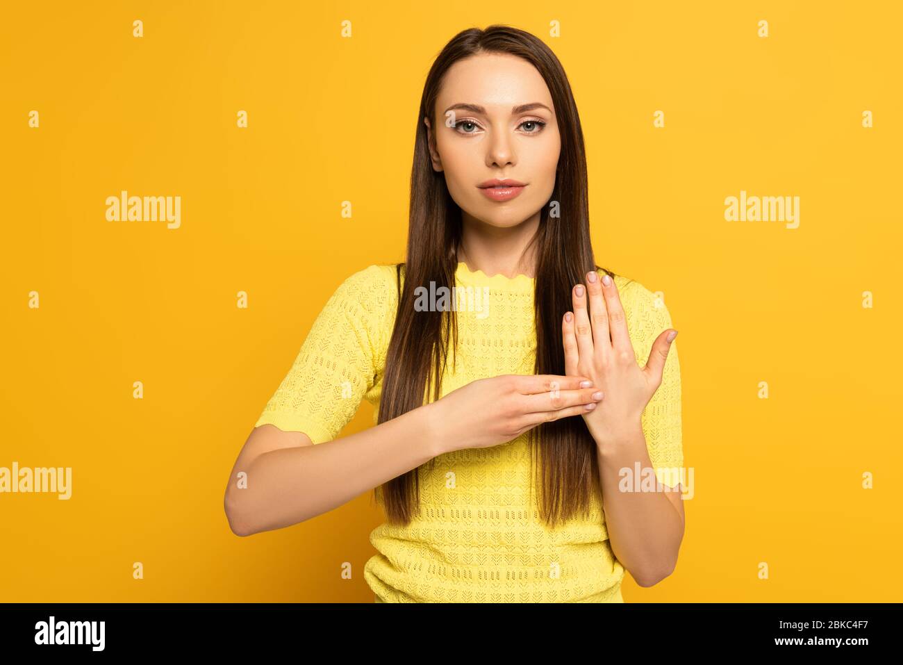 Attractive girl using sign language on yellow background Stock Photo ...