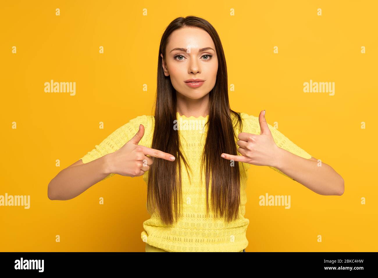Attractive girl gesturing while using sign language on yellow ...