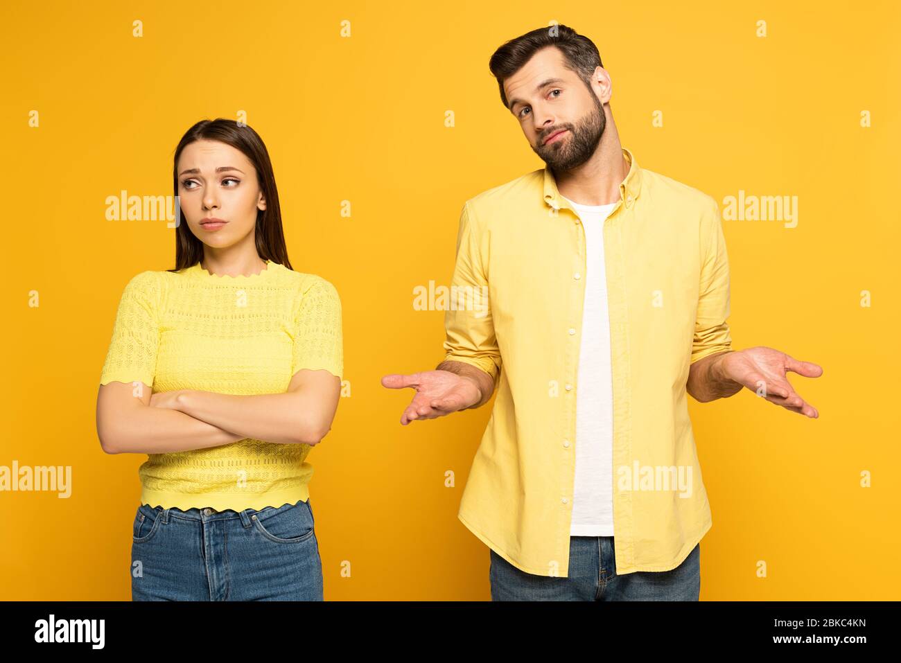 Confused man standing near spherical girlfriend on yellow background ...