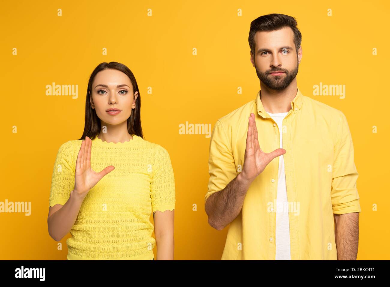 Young couple showing gesture in sign language on yellow background ...